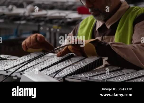 Medium shot of middle-aged black male factory worker assembling ...