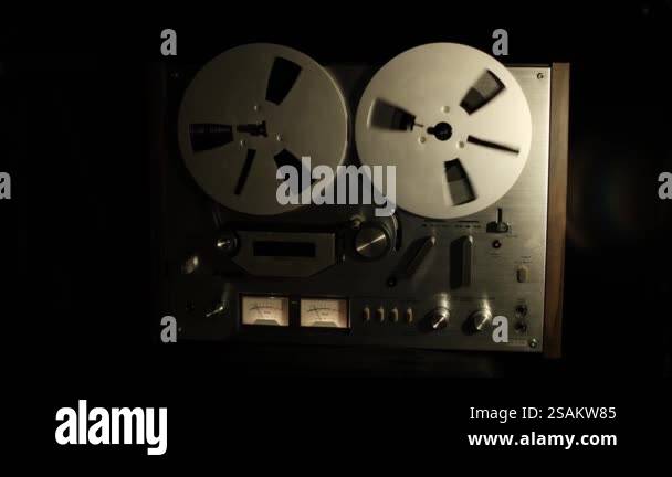 A vintage reel-to-reel tape recorder in action, with spinning spools ...