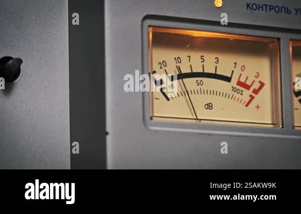 A close-up of a vintage VU meter with warm orange backlight. The analog ...