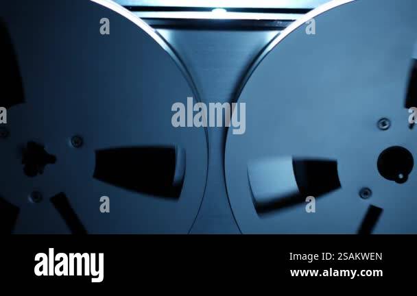 A dynamic wide shot shows both reels spinning on a reel-to-reel player ...