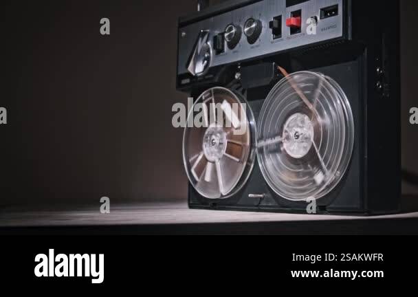 Close-up of a vintage reel-to-reel tape recorder playing music. The ...