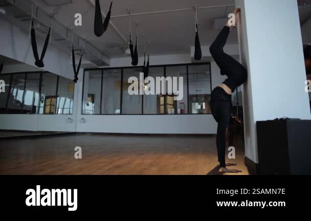 Young woman skillfully practicing perfect handstand against wall in ...