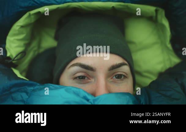 Person wake up in camp tent sleeping bag. Close up portrait of tourist ...