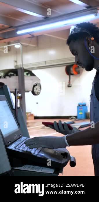 Mechanic uses a computer and talks on the phone while working in a busy ...