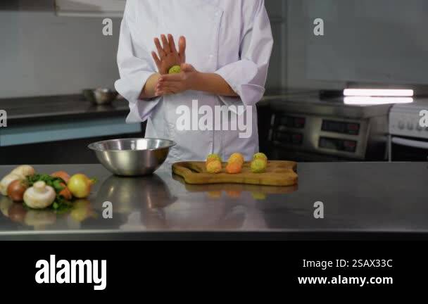 A chef in a white uniform shaping vibrant falafel balls by hand on a ...