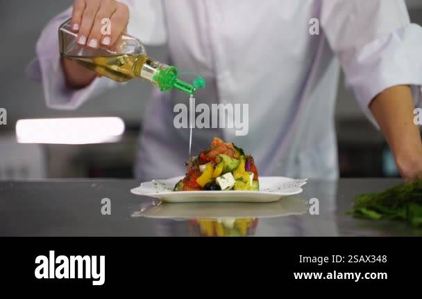 Close-up shot of a chefs hand pouring olive oil over a colorful ...
