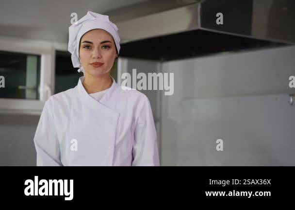 Close-up of a female chef wearing a white uniform and chef hat ...