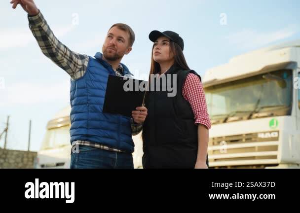 A logistics supervisor discusses routes with a truck driver, pointing ...