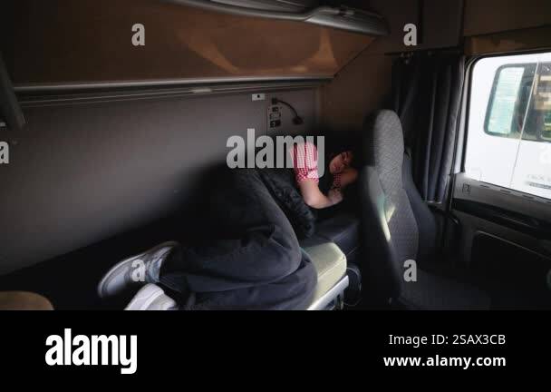 A female truck driver waking up from a nap inside the truck cabin ...