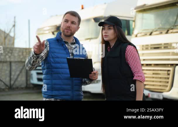 Two truck drivers review logistics documents on a clipboard while ...