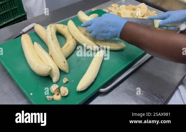 hands slicing fresh plantain with a knife, showcasing the traditional ...
