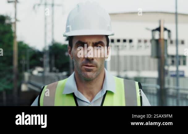 Portrait of man architect in safety helmet tilting head and speaking with boss on construction ...