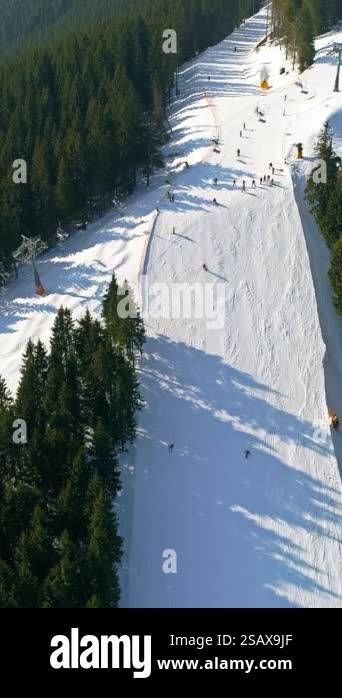 Aerial view of people snowboarding and skiing on a snowy ski slope at a ...