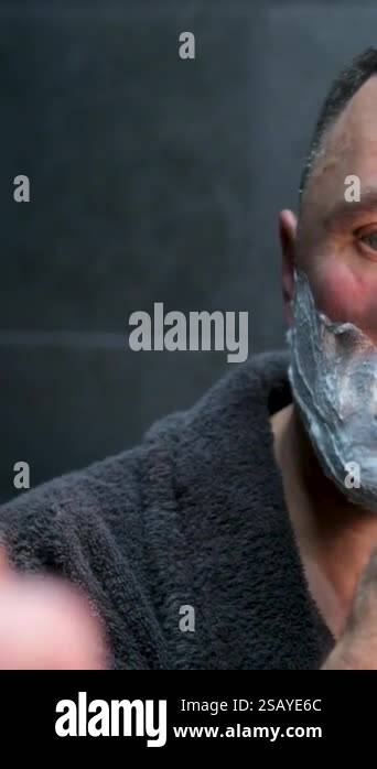 Man shaving beard using electric trimmer shaver. Male beauty grooming concept. Home lifestyle ...