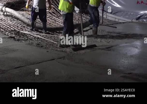 booted workers level and level concrete poured on the ground with flat ...