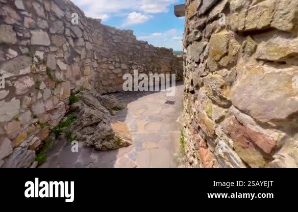 A narrow stone pathway winds through ancient castle ruins, with rugged ...