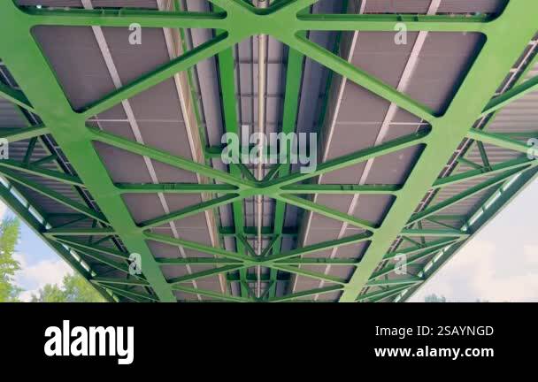 A close-up view of the underside of a green steel bridge, showcasing ...