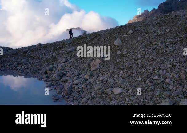 Aerial view to sporty woman with backpack hiking near lake on mountain ...