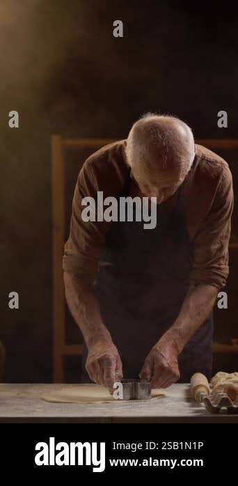Elderly man using a heart-shaped cookie cutter to cut pieces from ...