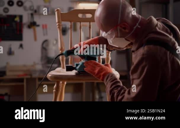 Carpenter sanding old wooden chair using electric sander during ...