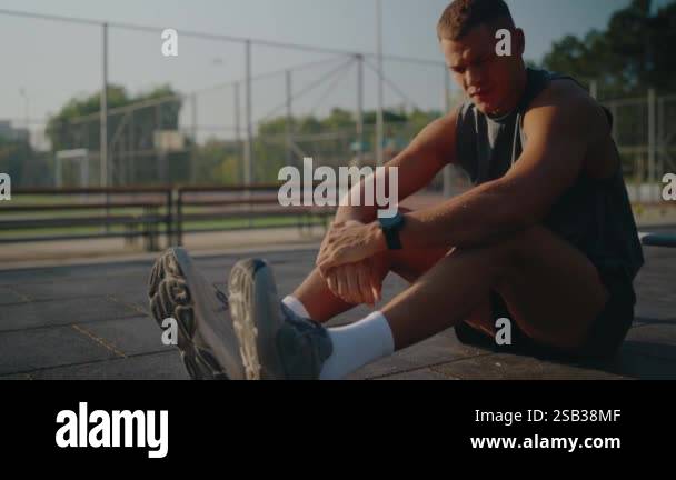 Young male athlete taking a break on an outdoor basketball court ...