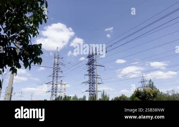 High voltage power lines stretch across a clear blue sky with scattered ...