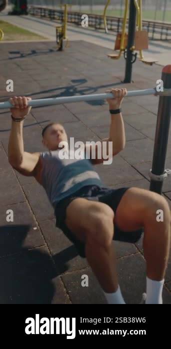 Young man performing an intense workout using a pull-up bar in an ...