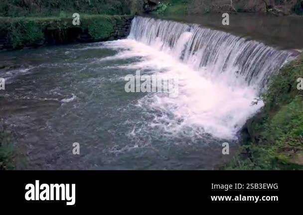A powerful flow of water cascades over a man-made weir near Cascata do ...