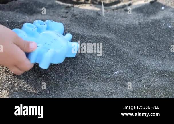 Child hands mold sand into the shape of crab on the sandy the beach ...