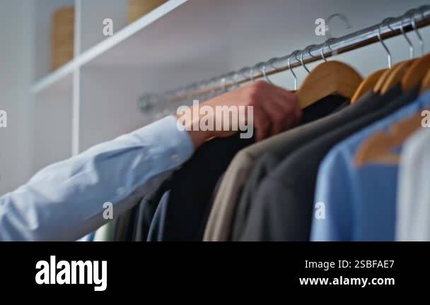 Man hands choosing clothes at large wardrobe closeup. Office guy ...