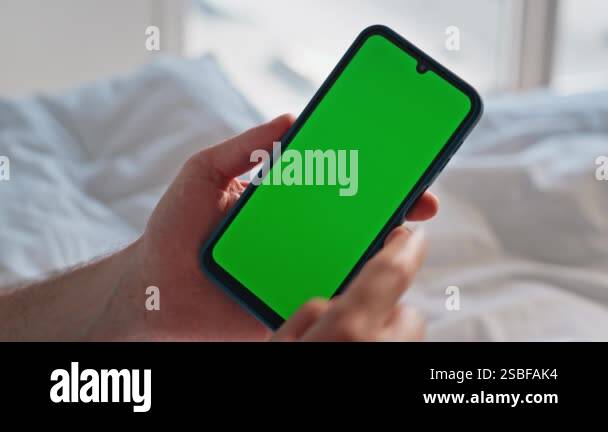 Unknown guy browsing greenscreen mobile phone app lying on cozy bedding ...