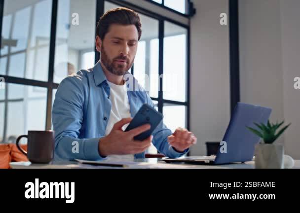 Smiling businessman working laptop keyboard checking mobile phone ...