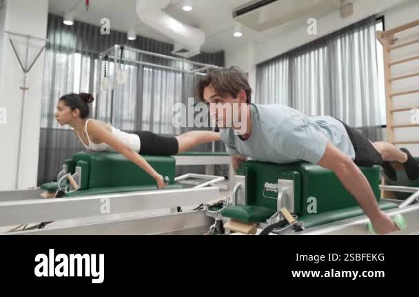 Man and woman practicing back extension exercises on pilates chair to ...