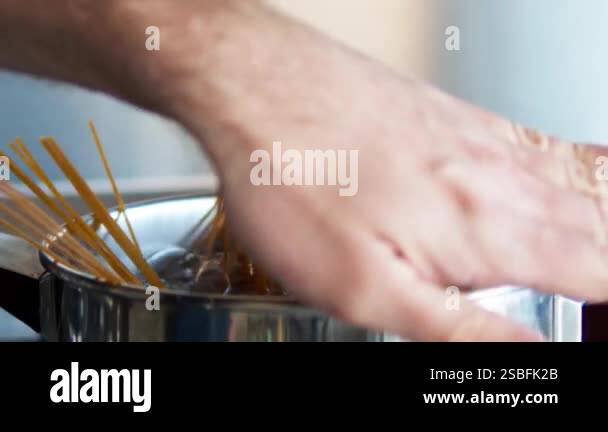 Hand pushing down spaghetti in the boiling water. Slow motion. Italian ...
