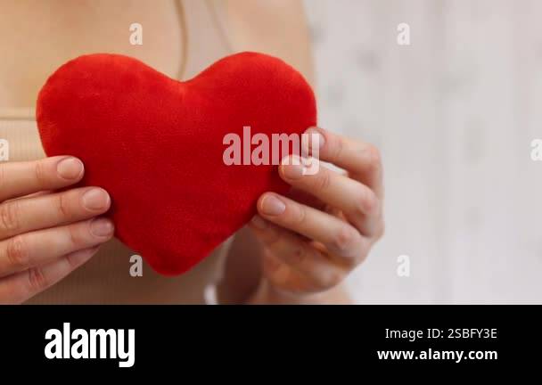 Toy heart in girl's hands. Plush soft heart in woman's hands, close-up ...