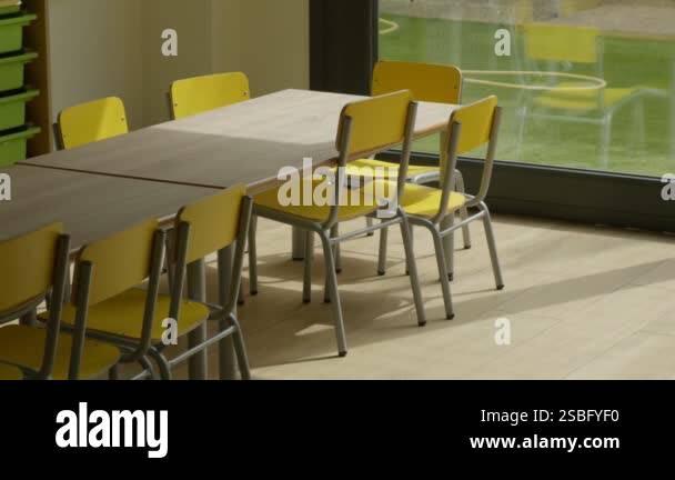 A stylish classroom interior featuring a long table and yellow chairs ...