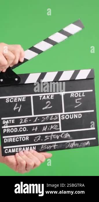 Film slate clapped against a vibrant green screen, signifying the start ...