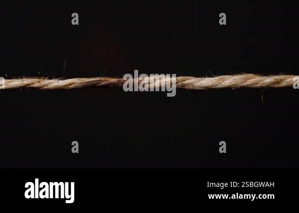 A rope ignited by fire with flames and glowing embers visibly burning ...