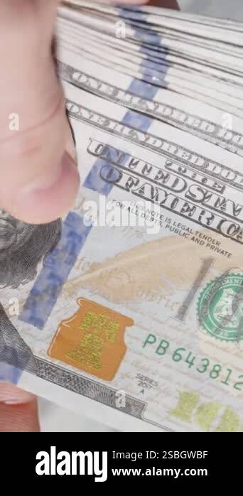 Vertical video. Close-up view of a hand holding a thick stack of crisp ...