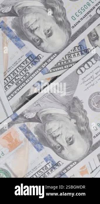 Vertical video. A stack of old hundred-dollar bills placed atop newer ...