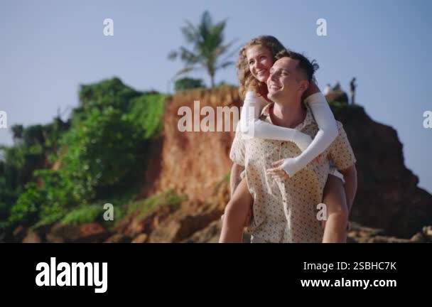 Happy husband carrying wife piggyback, running barefoot on tropical ...
