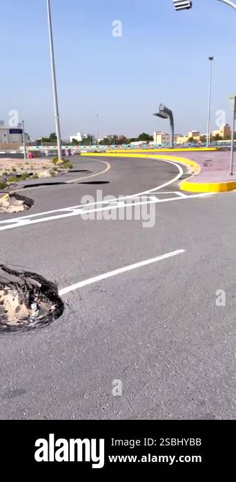 Damaged highway features prominent hole and multiple asphalt cracks ...