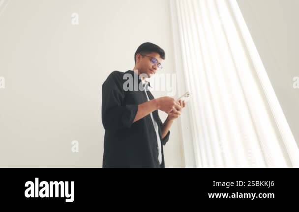 Young Indian Gen Z man in stylish casual wear stands near a bright ...