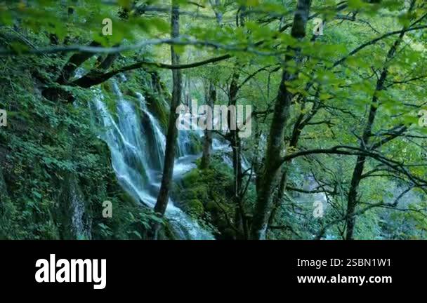 A peaceful waterfall flowing into a lake. Plitvice National Park ...