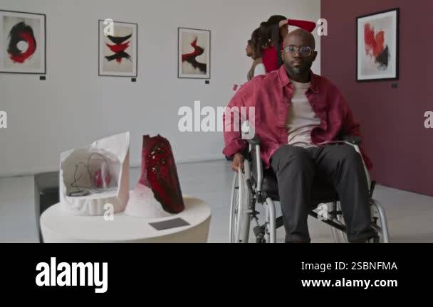 African American man in wheelchair getting closer to examine abstract ...