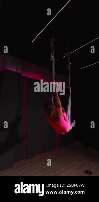 woman in a red silk dress doing aerial dance on a pole with smoke and a ...