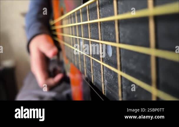 Guitar strings in close-up, a hand playing the guitar in the background ...