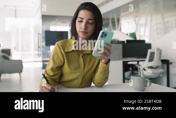 Female office employee holding smartphone, gains new knowledge ...