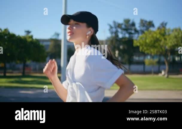 Smiling girl running city sunny road listening music in wireless ...