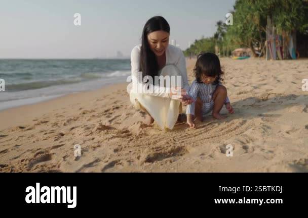 mother and toddler baby girl play with shell on the sea beach in ...